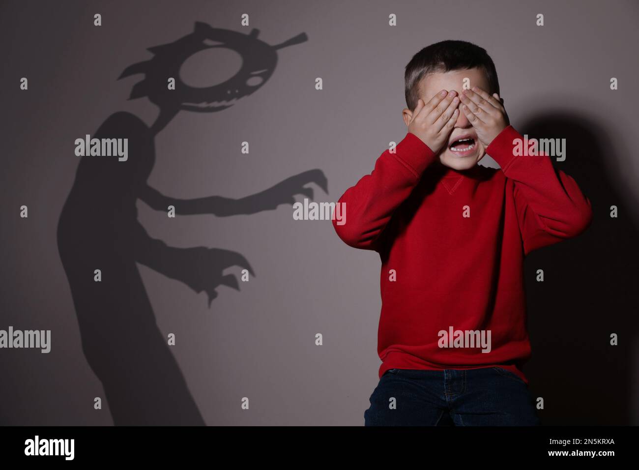 Shadow of monster and scared little boy on beige background Stock Photo ...