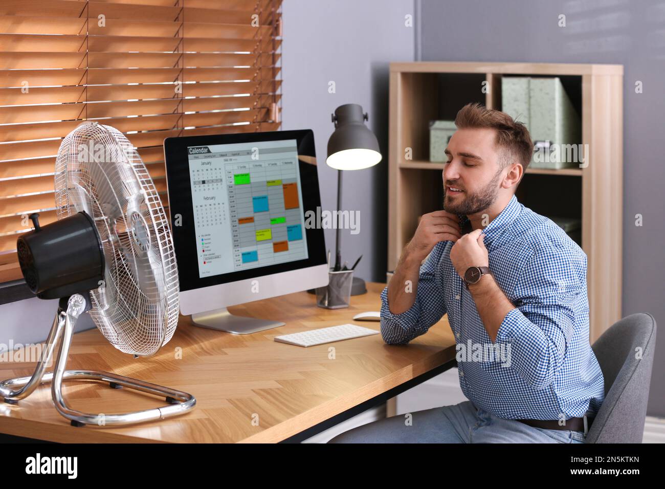 Man enjoying air flow from fan at workplace Stock Photo - Alamy