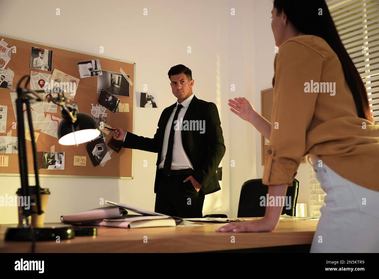 Detective working with client in his office Stock Photo - Alamy