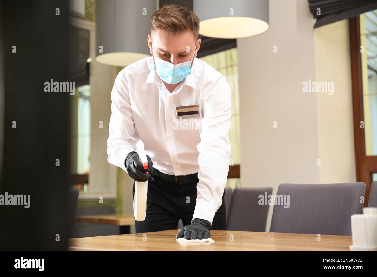 Waiter cleaning table with rag and detergent in restaurant. Surface ...