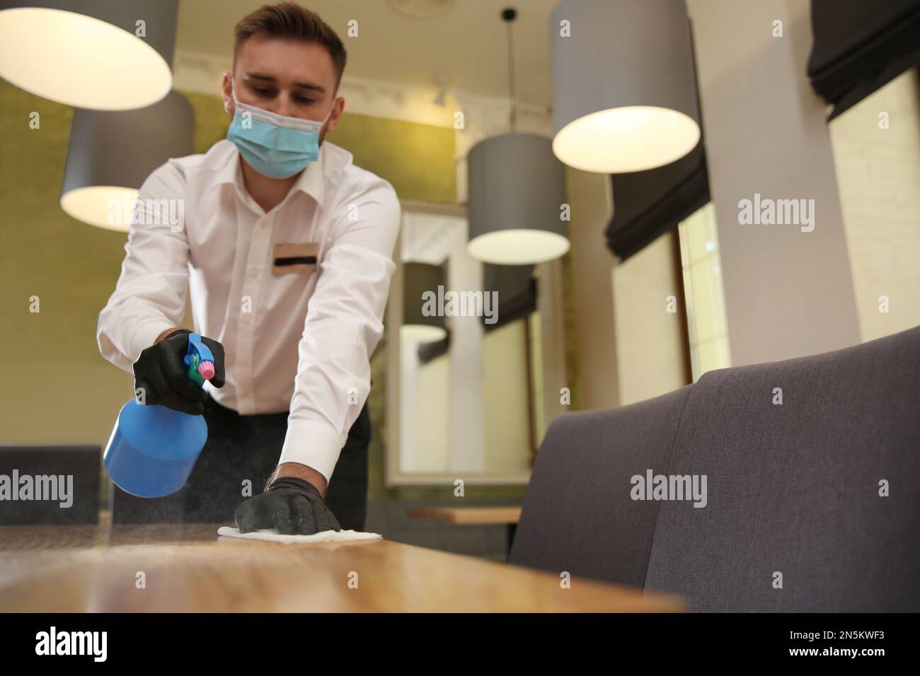 Waiter cleaning table with rag and detergent in restaurant. Surface ...