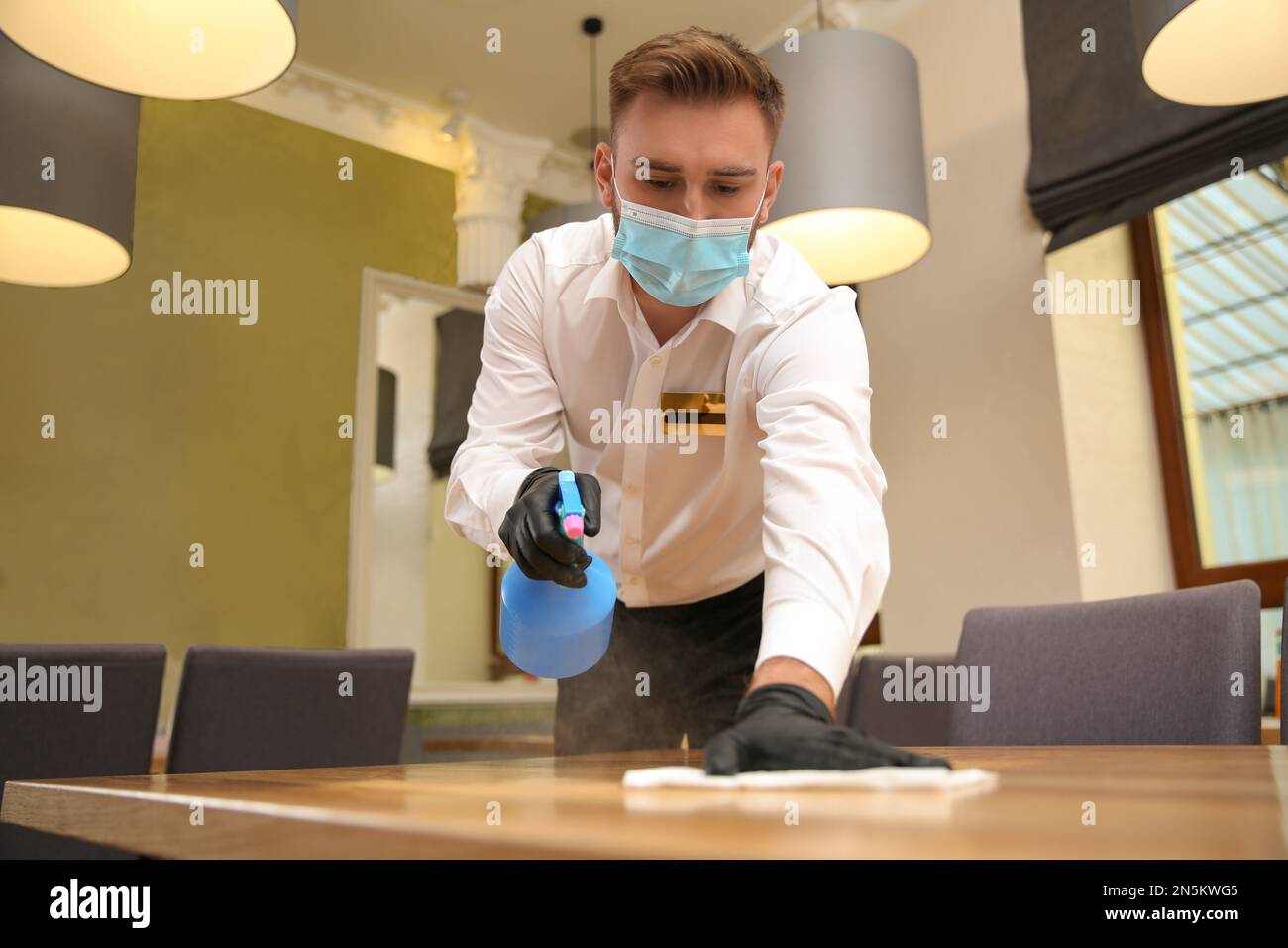 Waiter cleaning table with rag and detergent in restaurant. Surface ...