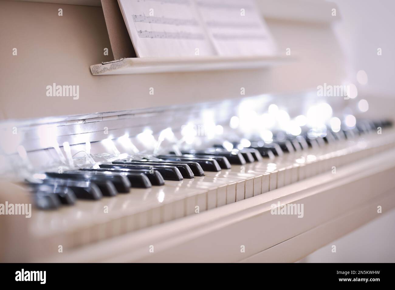 Glowing fairy lights on piano keys, closeup. Christmas music Stock ...
