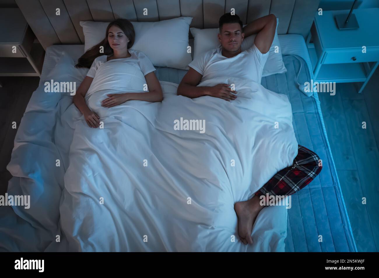 Couple sleeping on electric heating pad in bed at night, above view ...