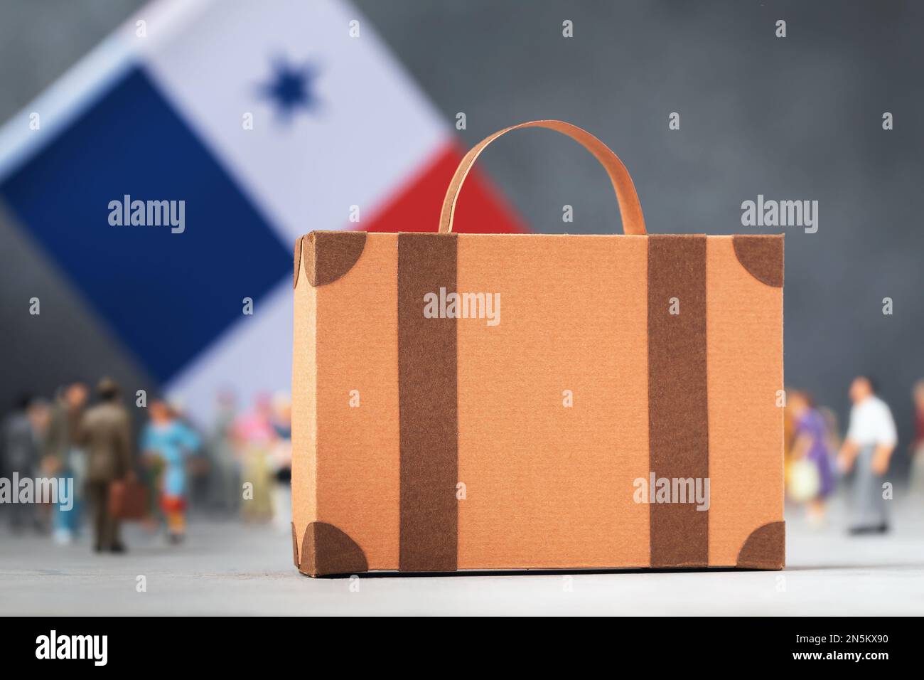 Cardboard suitcase, plastic toy people and a flag on an abstract ...