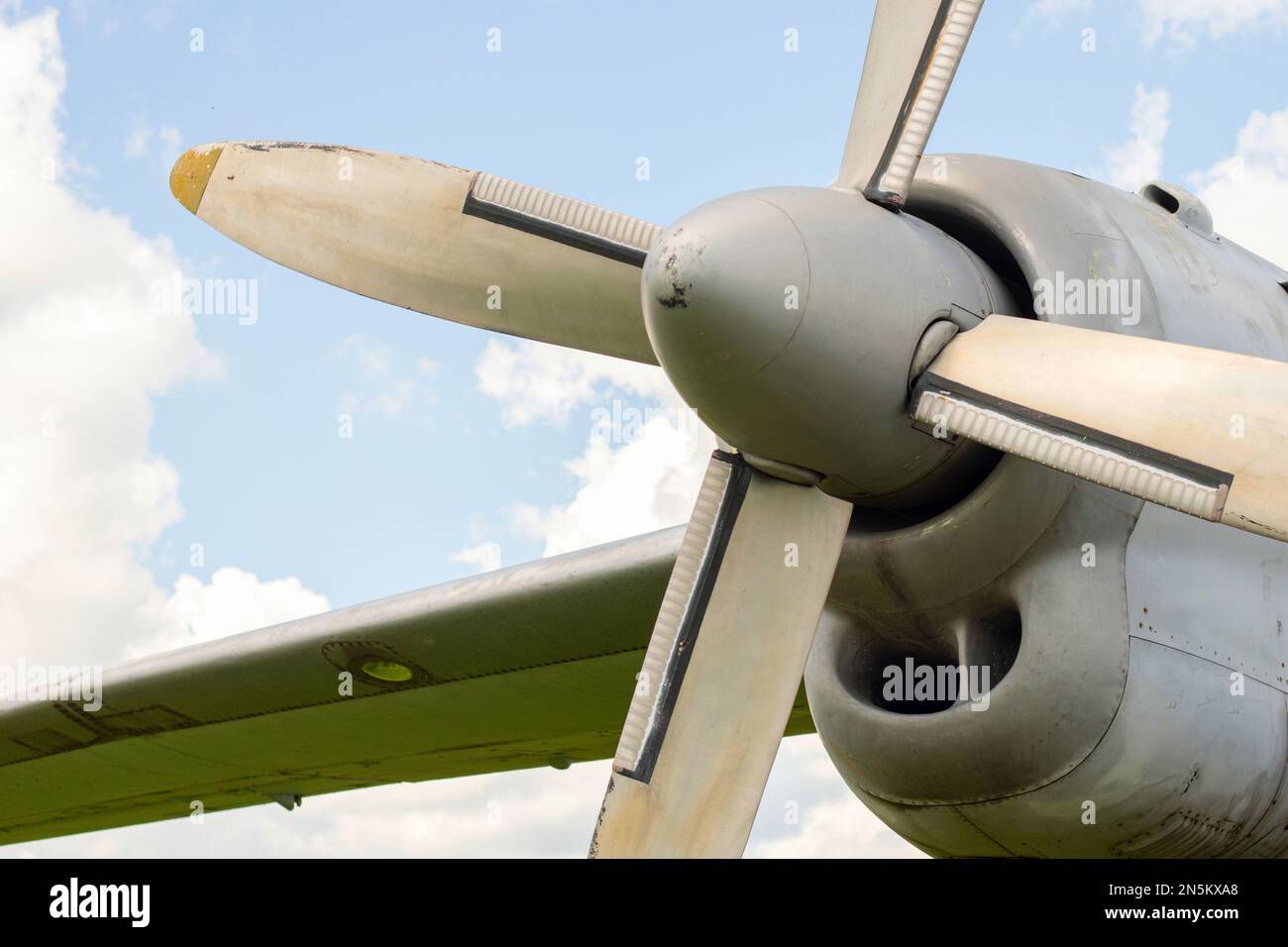 A fragment of airplane wing with four-bladed aircraft propeller against ...