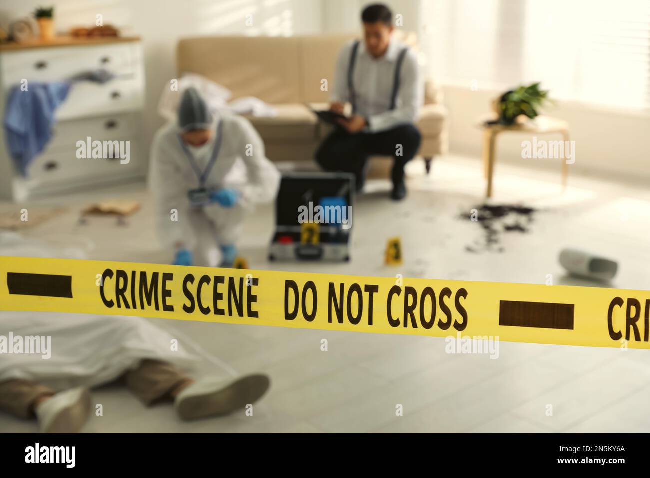 Investigators working at crime scene with dead body, focus on yellow ...