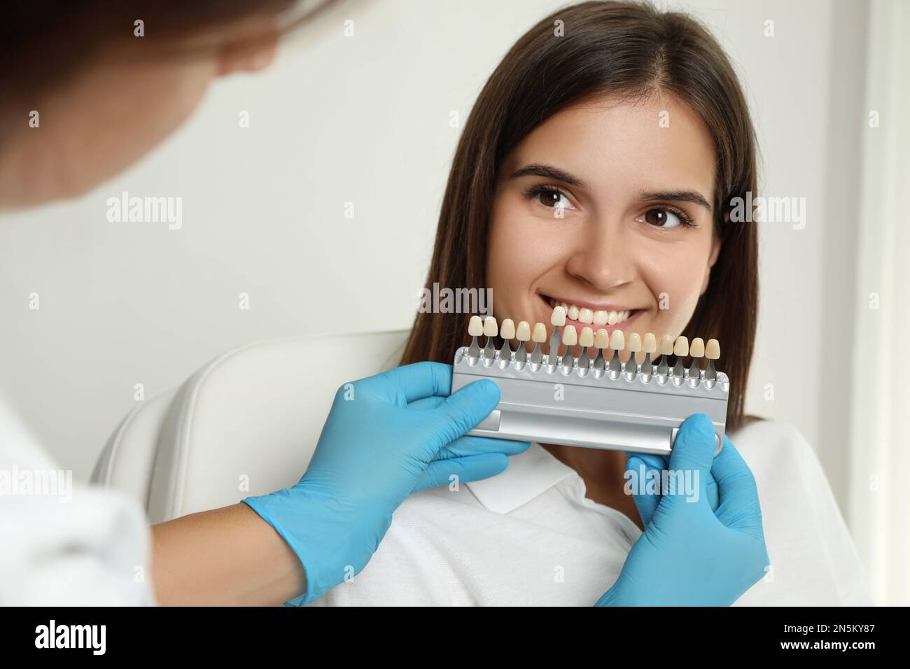 Doctor checking young woman's teeth color in clinic. Cosmetic dentistry ...