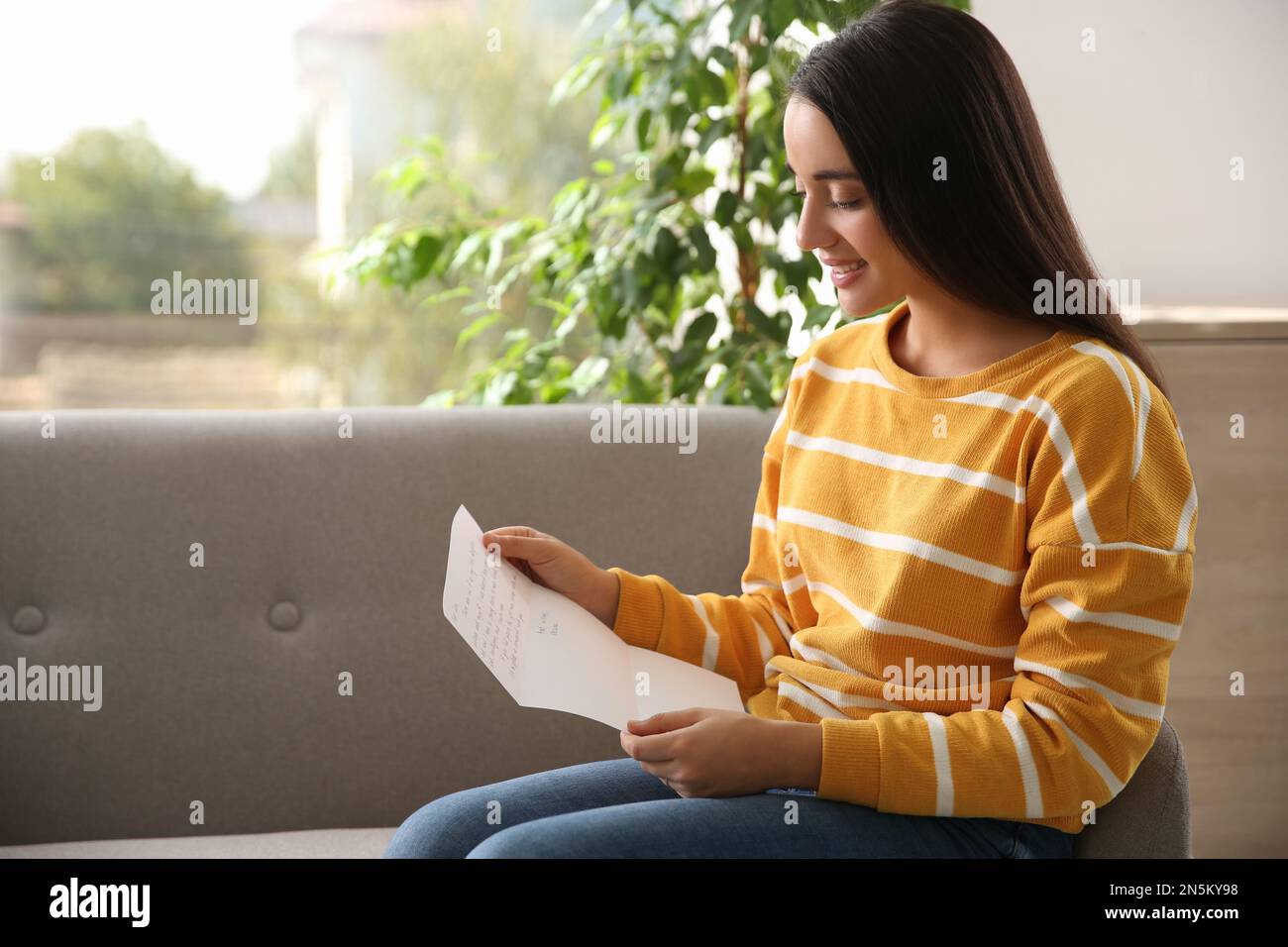Woman reading letter on sofa at home Stock Photo - Alamy