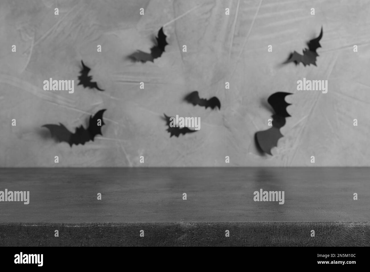 Stone table near grey wall with black paper bats. Halloween decoration ...