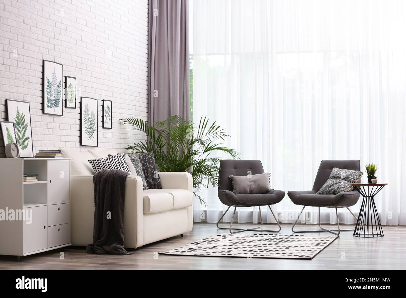 Comfortable sofa and chairs near window with elegant curtains in room ...