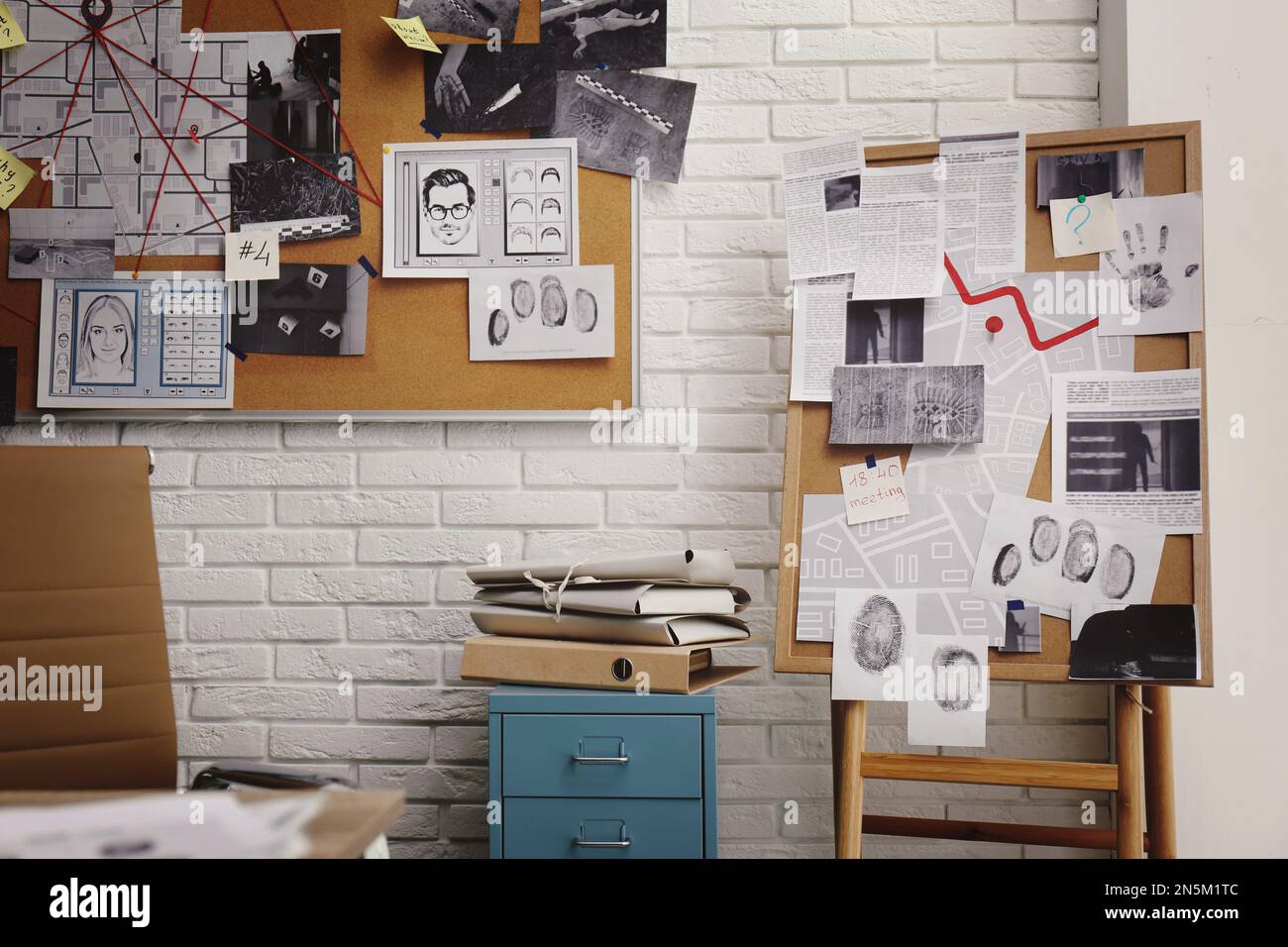 Boards with crime scene photos and maps near white brick wall in ...
