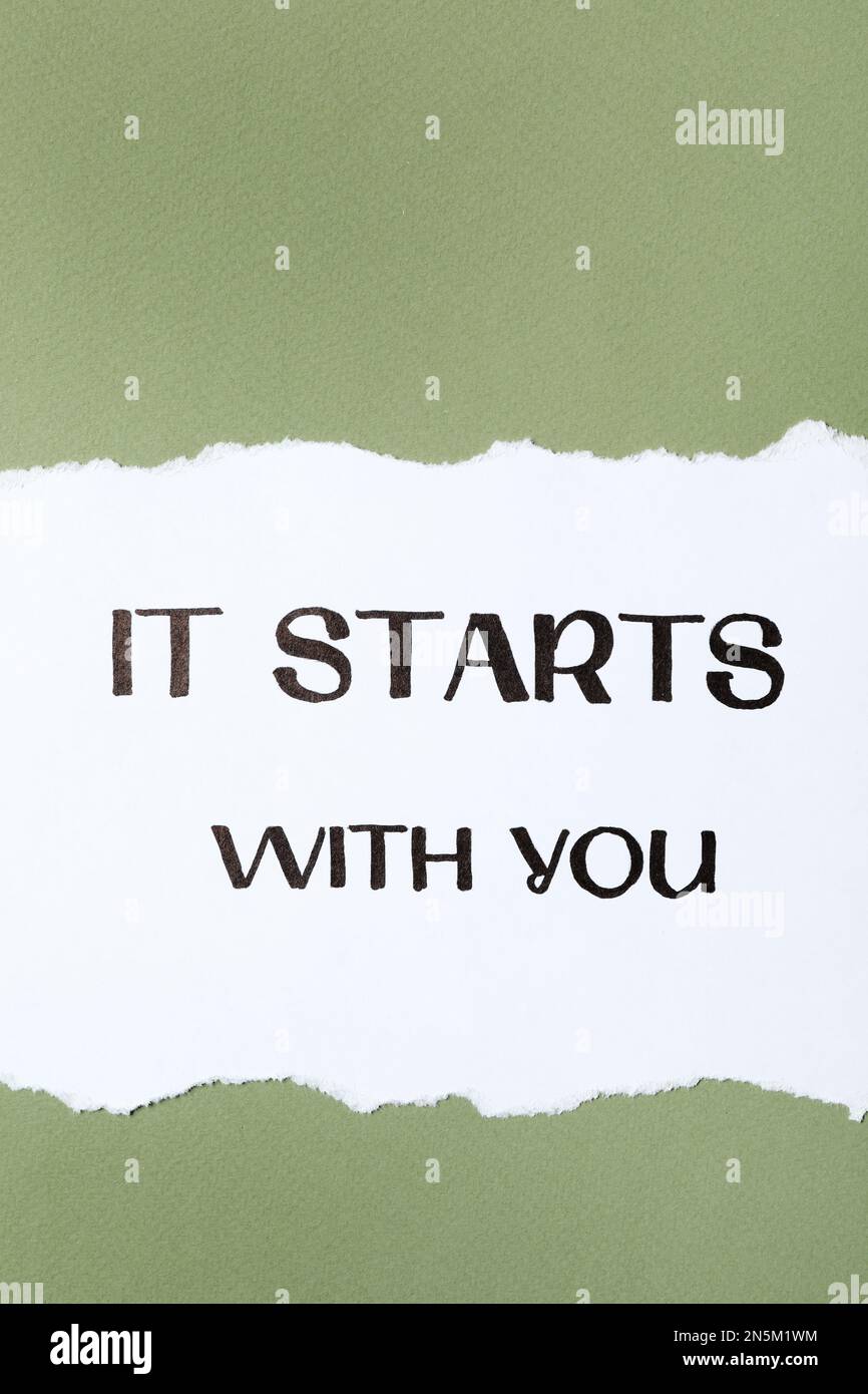 Sheet of paper with phrase It Starts With You on green background, top ...