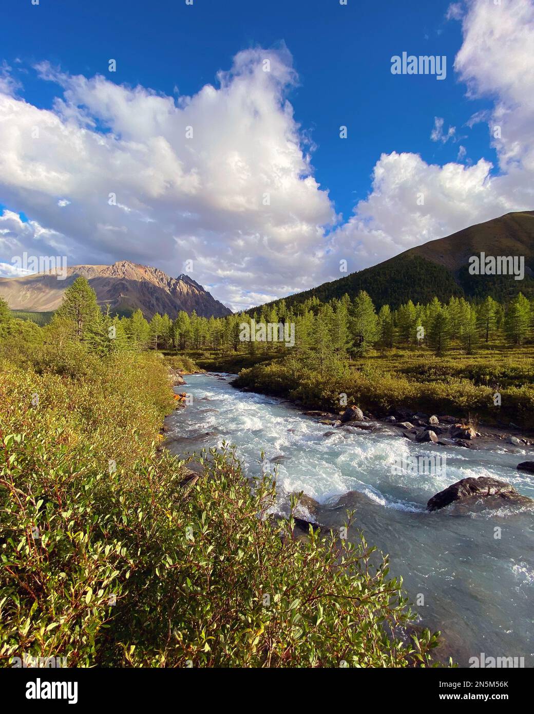 Alpine river with rifts in a mountain valley with high rocks among the ...
