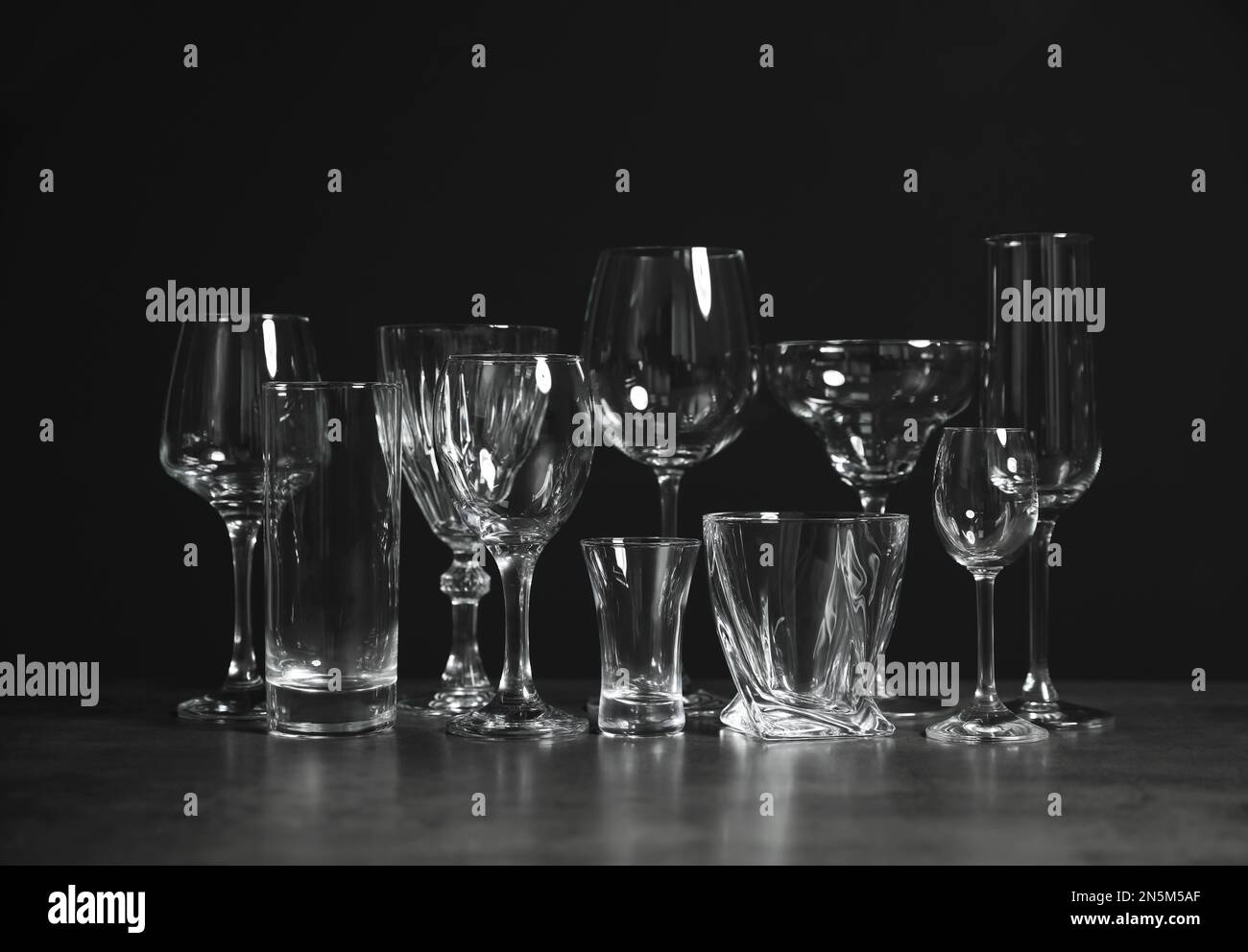 Set of bar glassware on table against dark background Stock Photo - Alamy