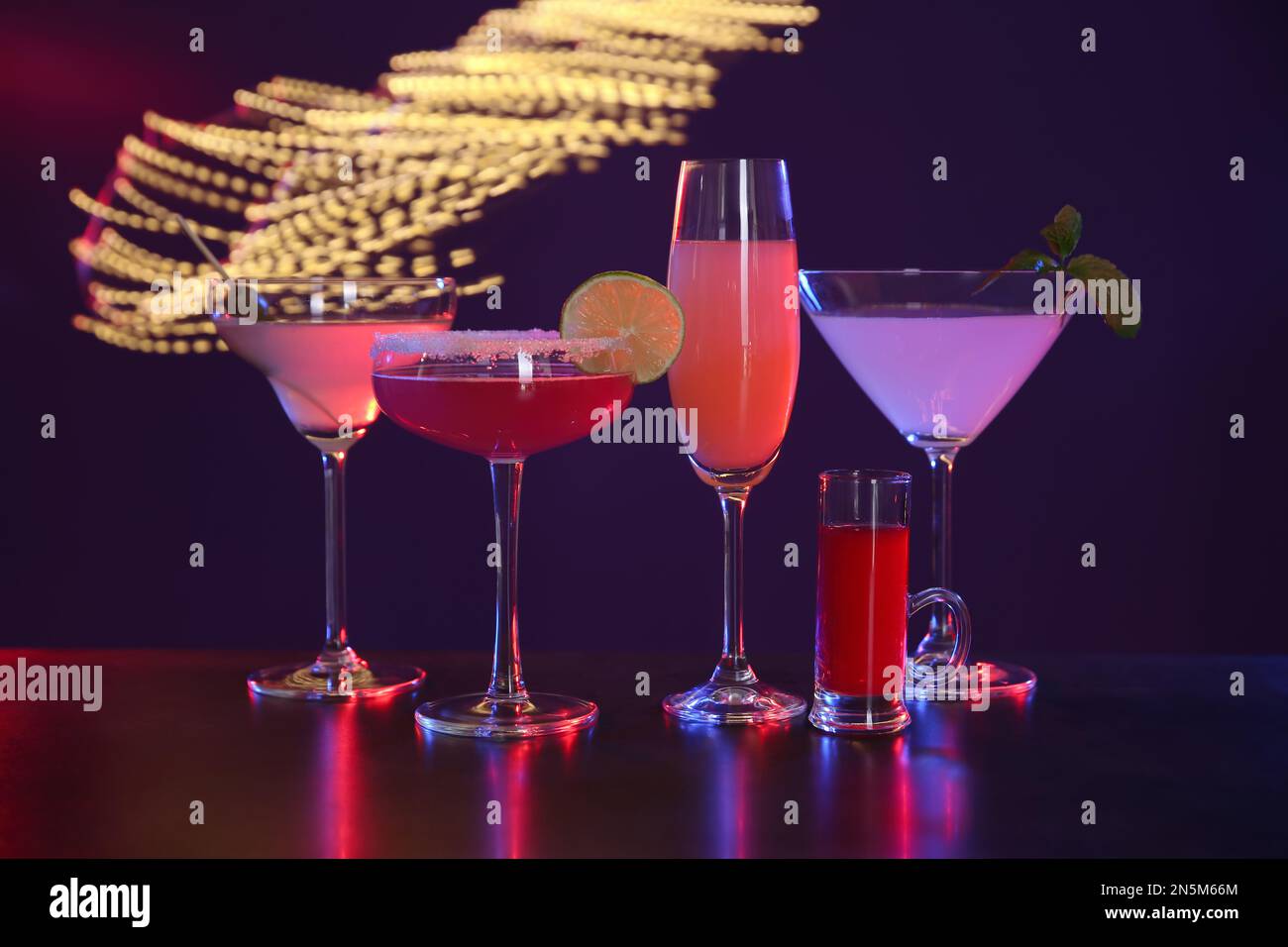 Many different alcoholic drinks on table against dark background with ...