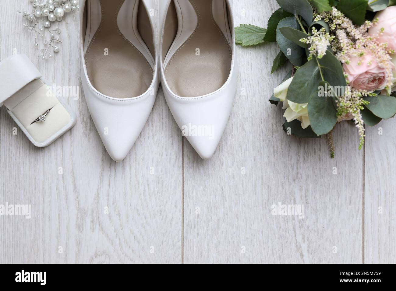 Flat lay composition with wedding high heel shoes on white wooden floor ...