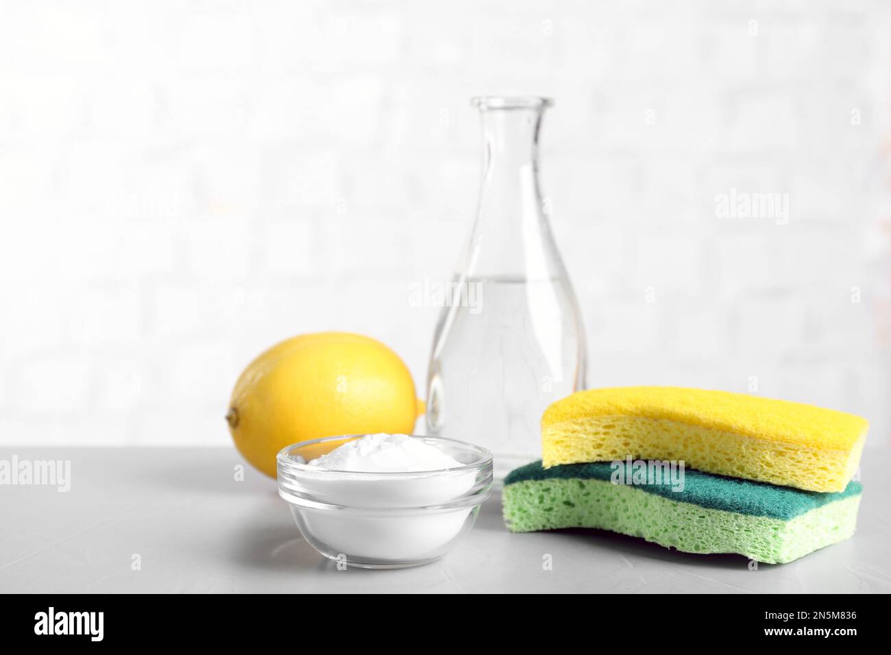 Baking soda, lemon, vinegar and sponges on light grey table Stock Photo ...