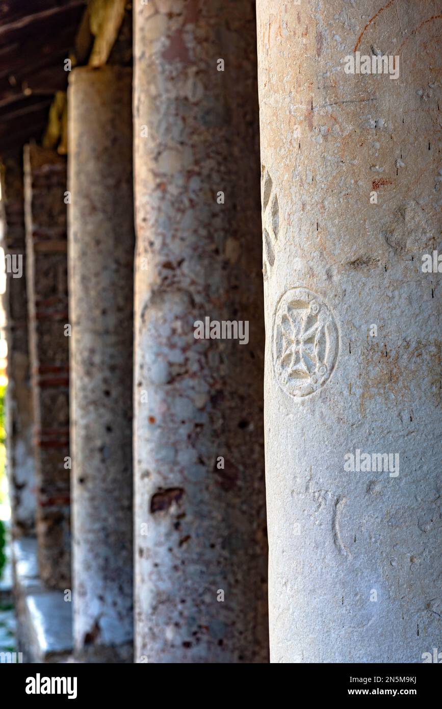 A vertical shot of carved cross on ancient pillar with other pillars in ...