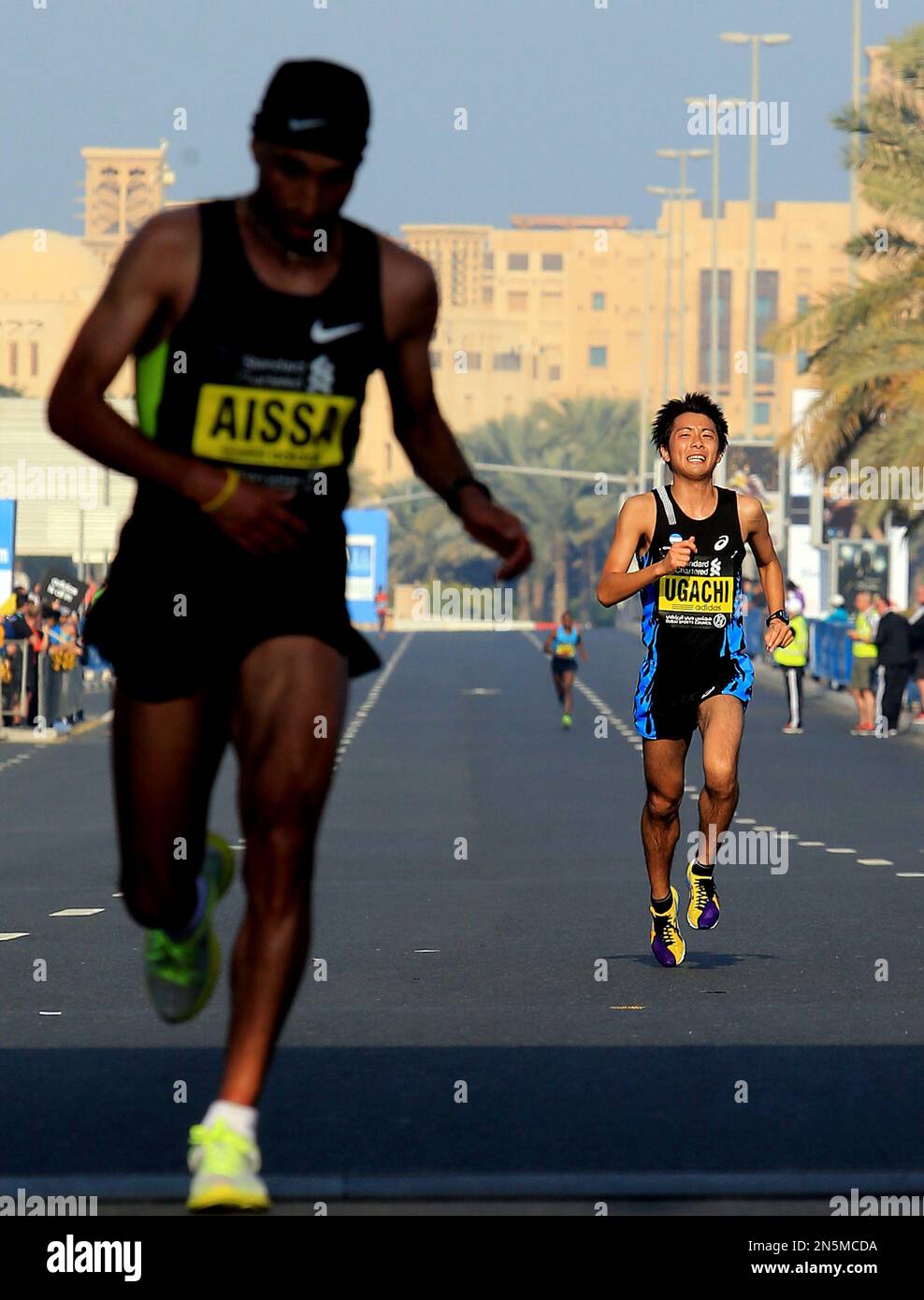 Japanese runner Tsuyoshi Ugachi, right, crosses the finish line at the ...