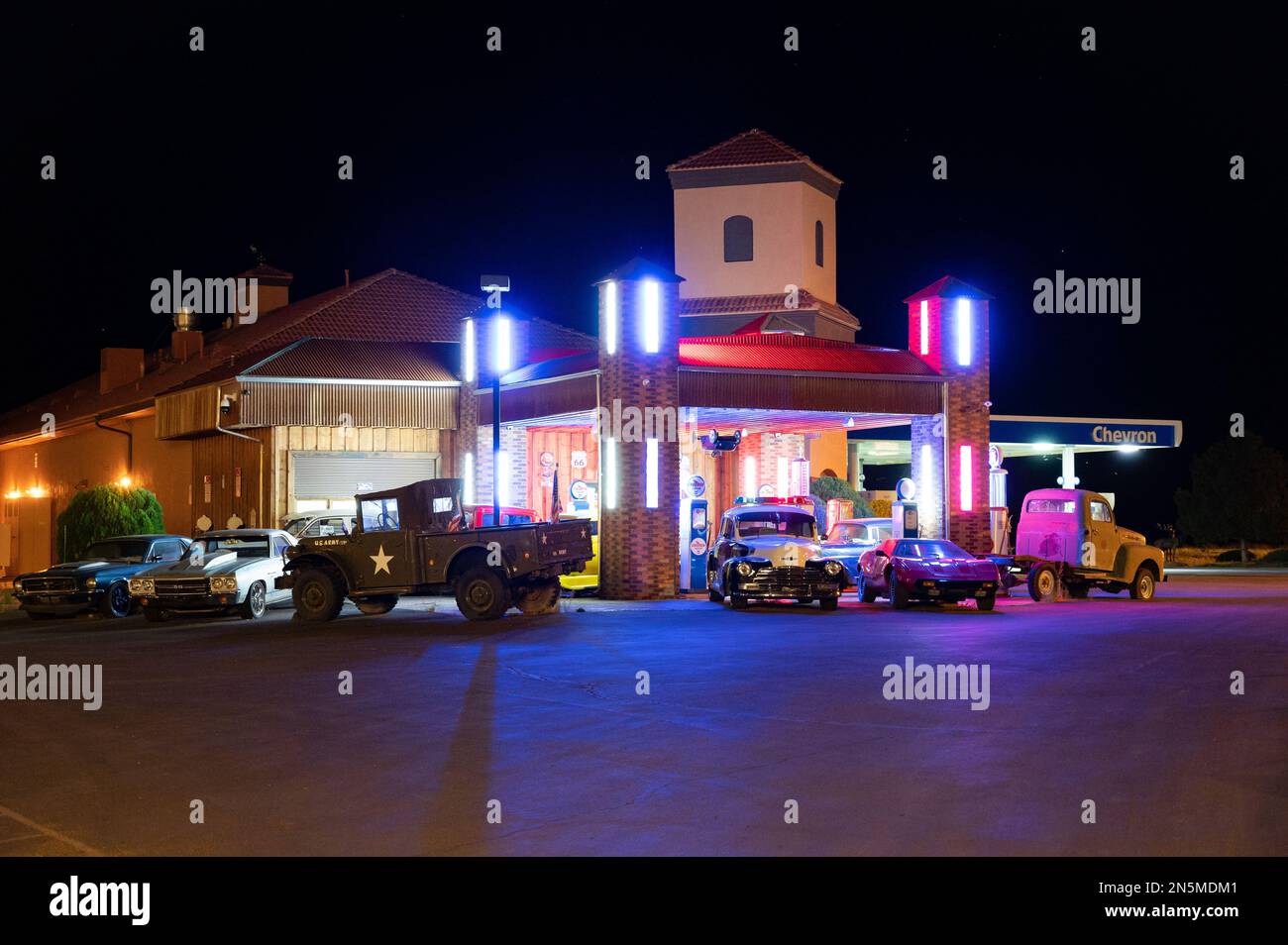 An old chevron roadside gas station with vintage cars at night Stock ...