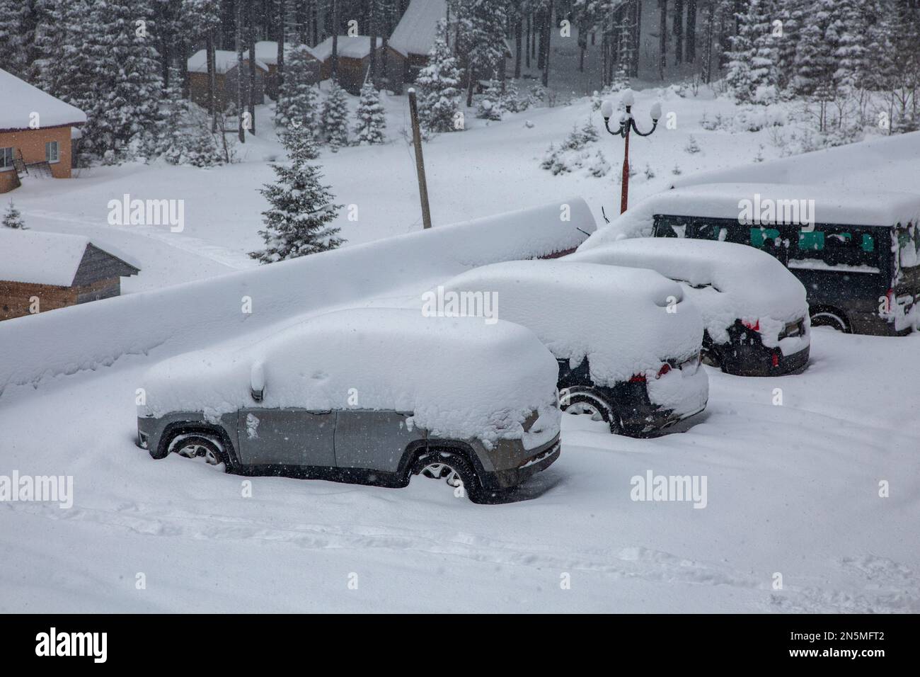 Car under a thick layer of snow. Snow-covered vehicles during a winter ...