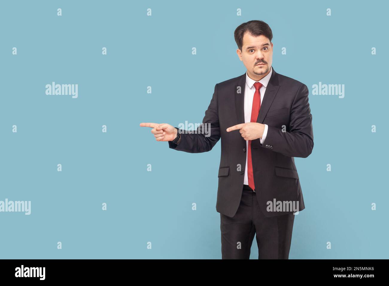 Serious strict man with mustache standing pointing aside at ...