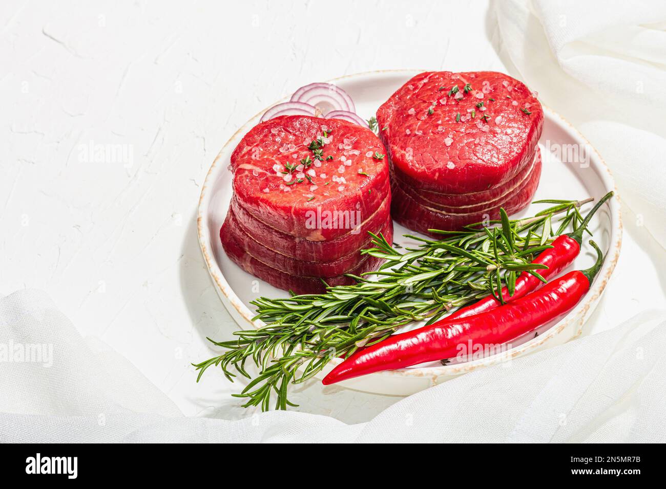 Raw Eye of round steak with spices and herbs on white background. Fresh ...