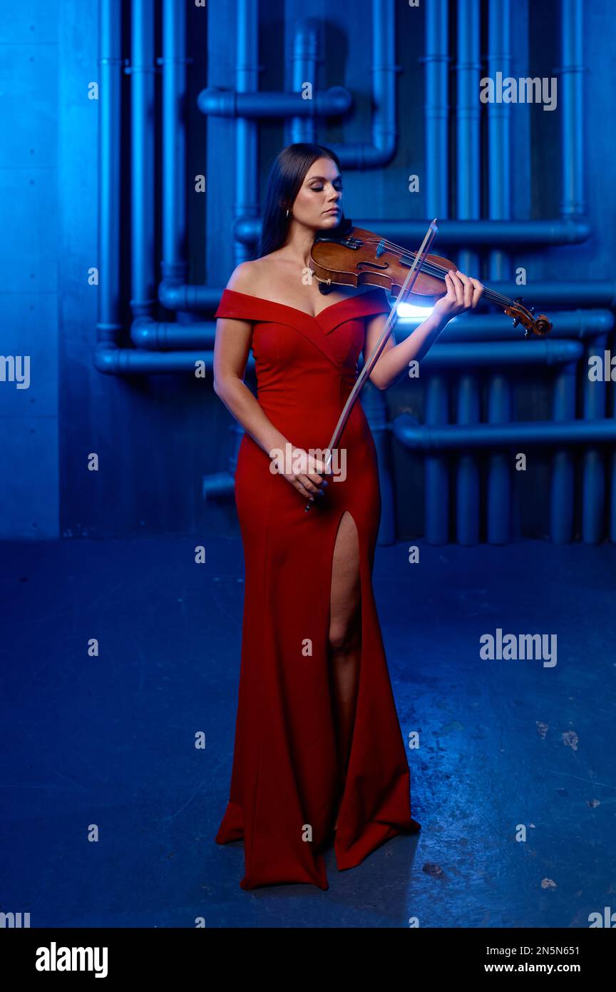 Young pretty woman playing violin solo over loft interior background ...