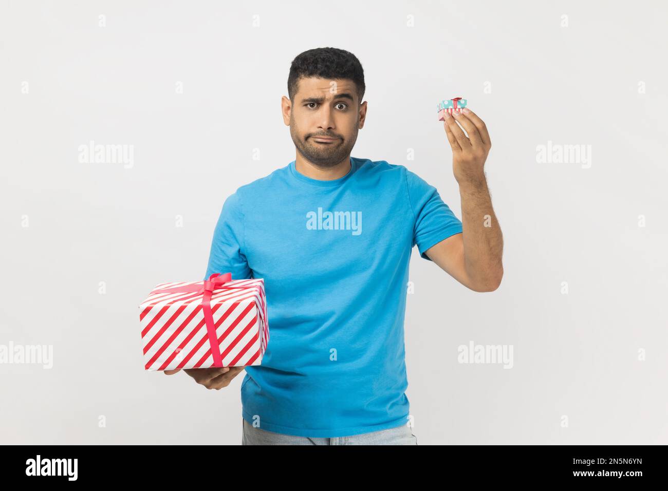 Portrait of puzzled attractive man wearing blue T- shirt standing ...
