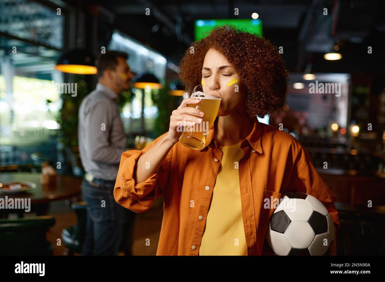 Young girl football fan drinking beer while rest in sports bar with ...