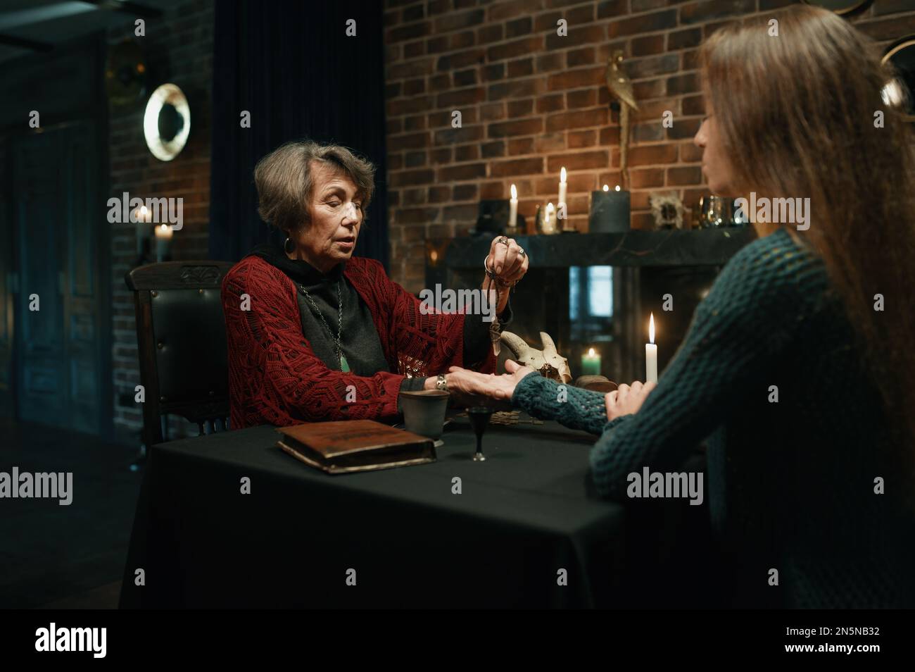 Mature witch using crystal pendulum to predict future for client Stock ...