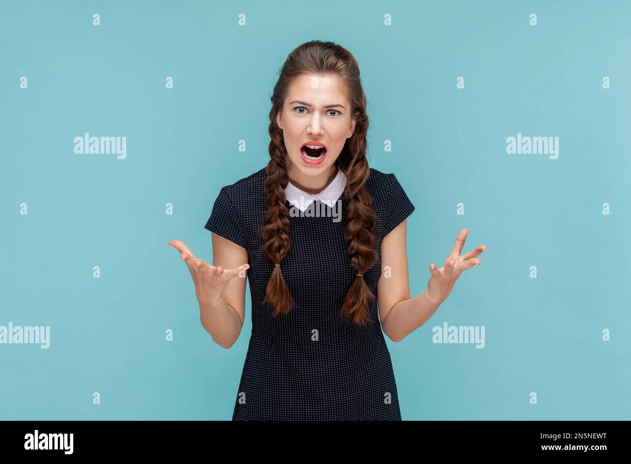 Portrait of angry attractive woman with braids standing with raised ...