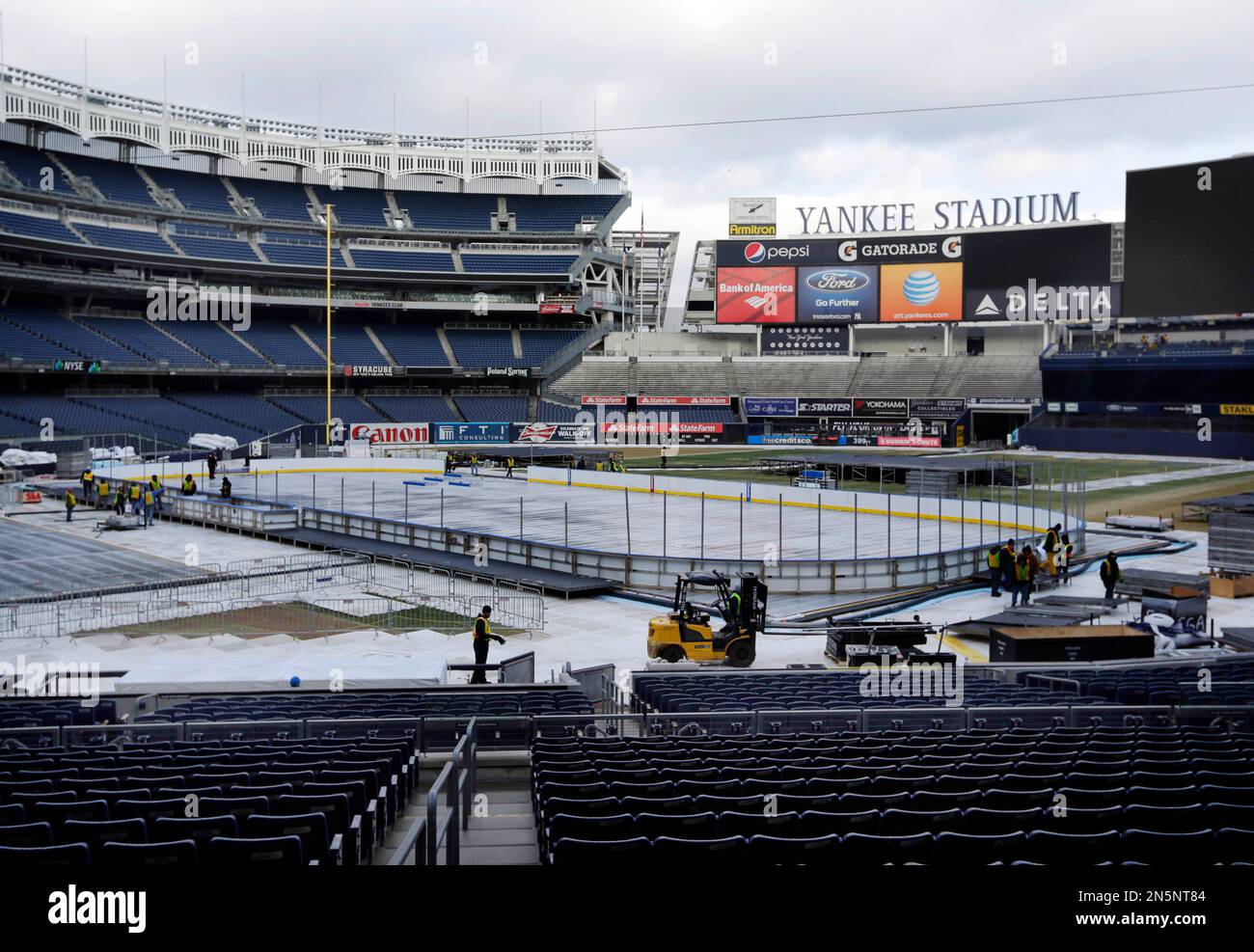 Workers install an outdoor hockey rink on the infield of New York's ...