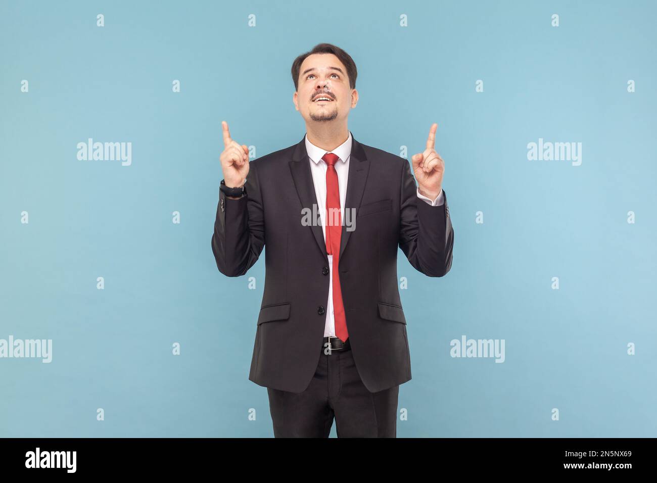 Portrait of young adult man with mustache standing looking up ...