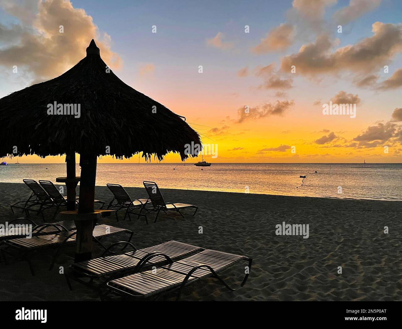 Looking across a beach in Aruba at the sun setting over the Caribbean ...