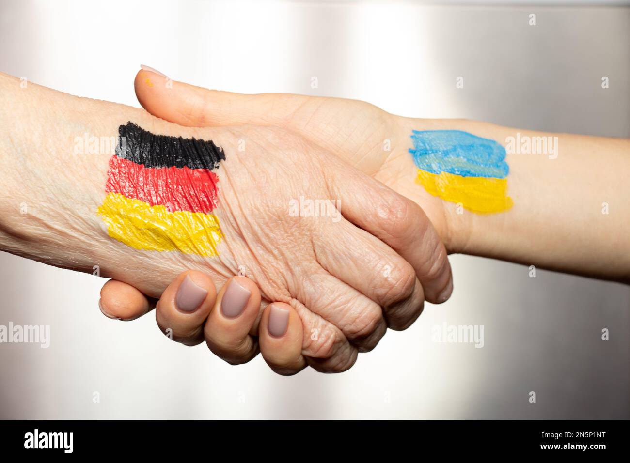 Two hands one with a drawn flag of Germany and the second with a drawn ...
