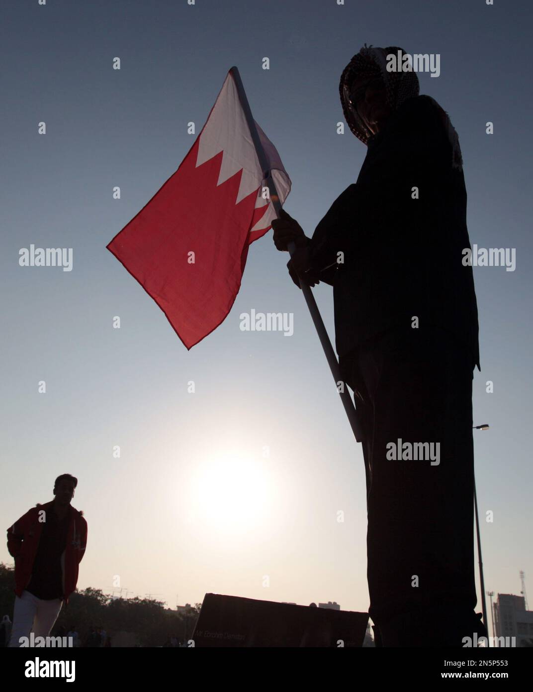 An elderly Bahraini man holds a national flag as he waits for a march ...