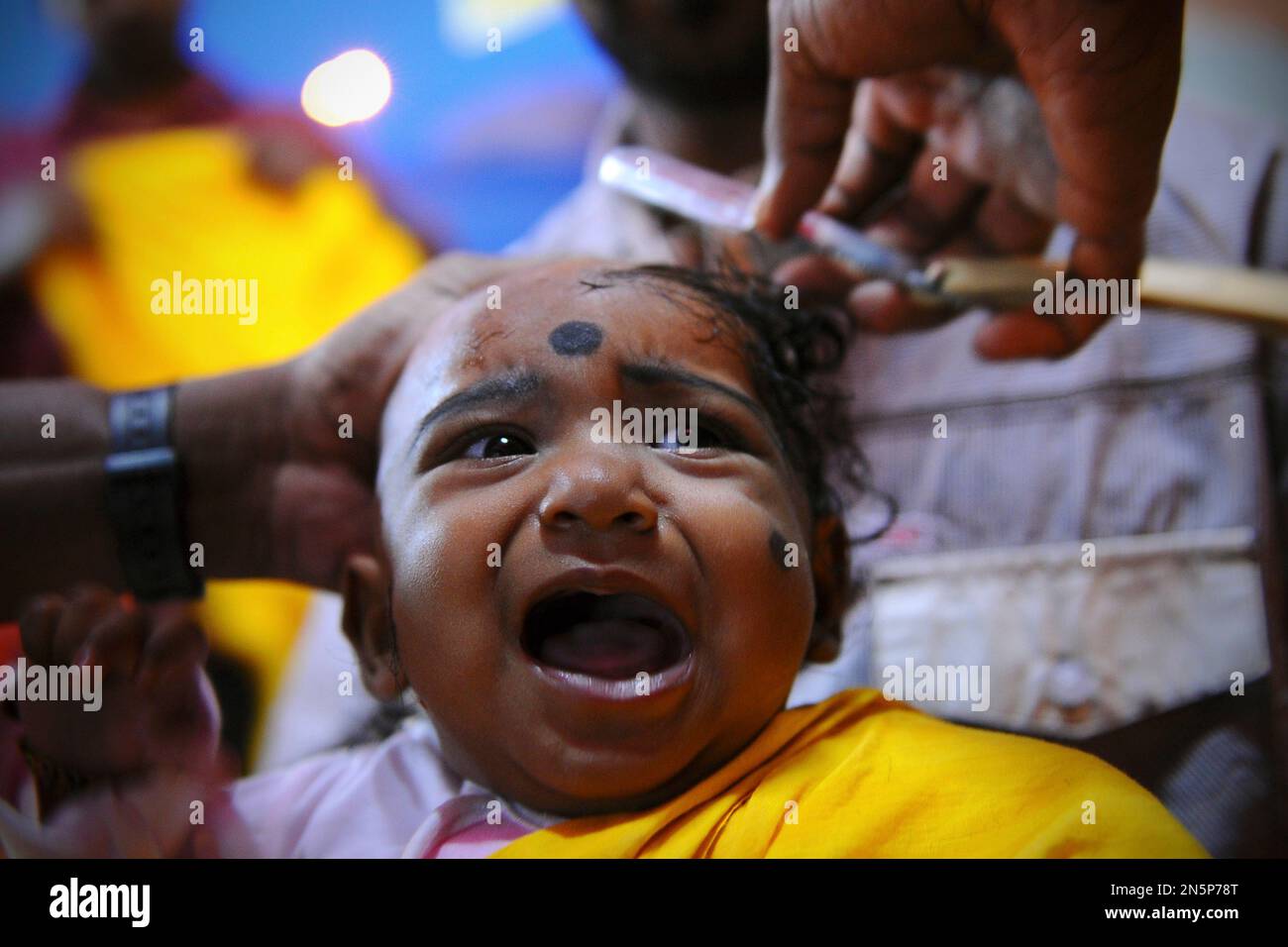 A child goes through "Mundan," a traditional Hindu head shaving ritual ...