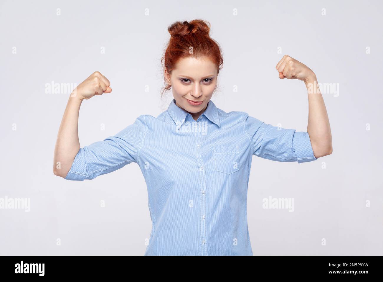 Portrait of strong confident young adult ginger woman wearing blue ...