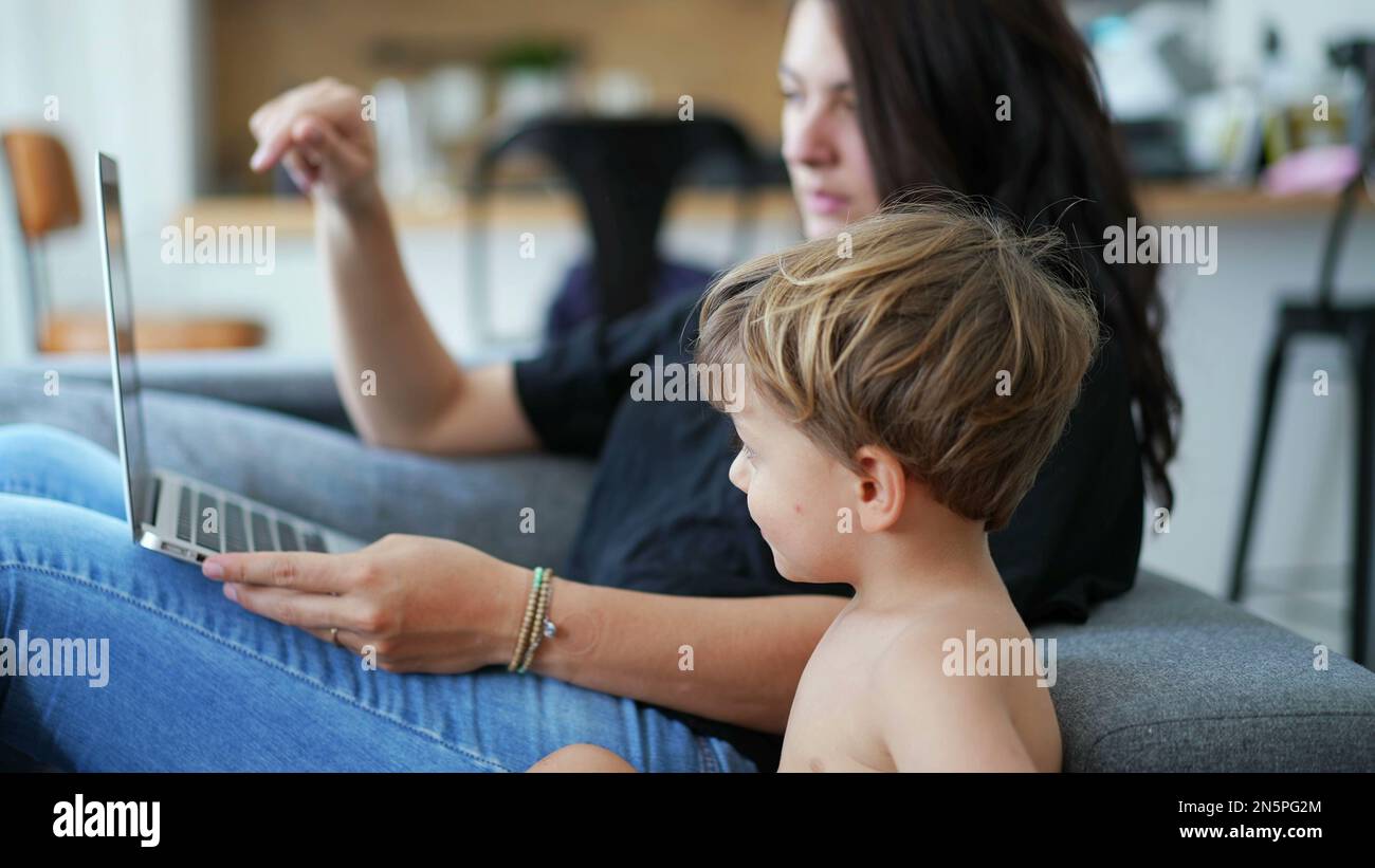 Mother parenting with child in front of laptop screen working from home ...