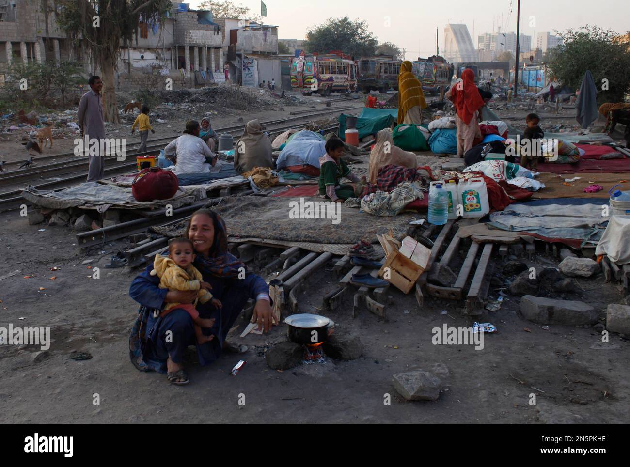 A homeless Pakistani woman cooks food in a poverty area set up along ...