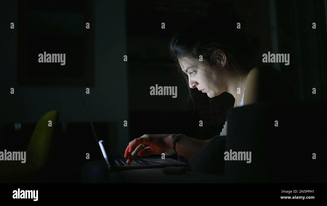 Woman working at night in front of laptop. Person using computer ...