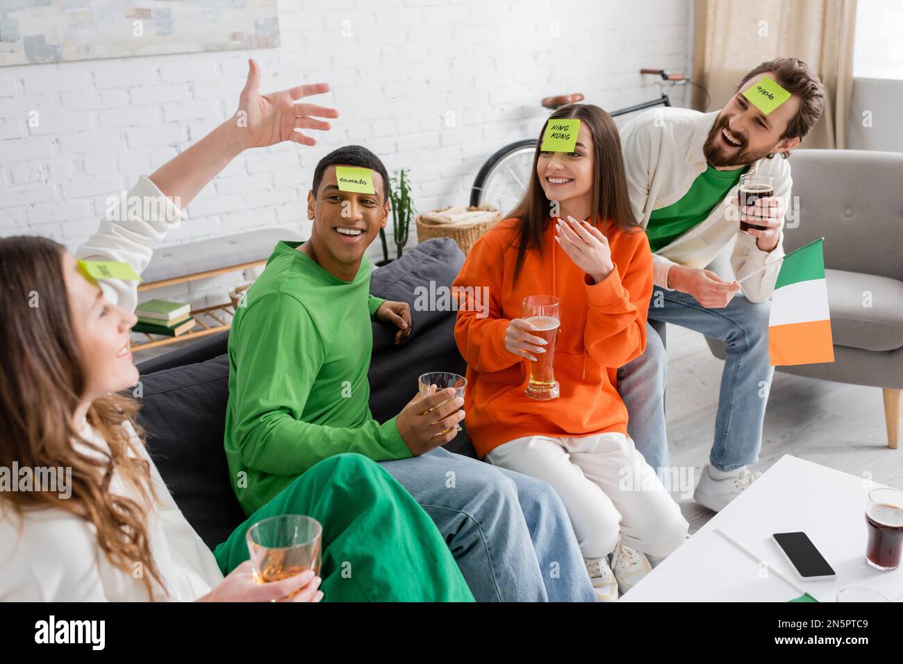 happy interracial friends with sticky notes on foreheads looking at ...