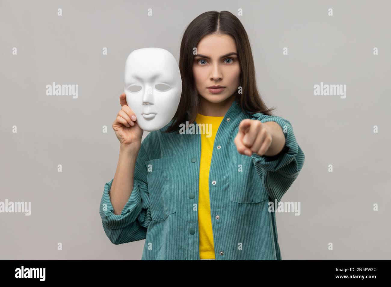 Portrait of bossy woman with dark hair holding white mask in hand ...