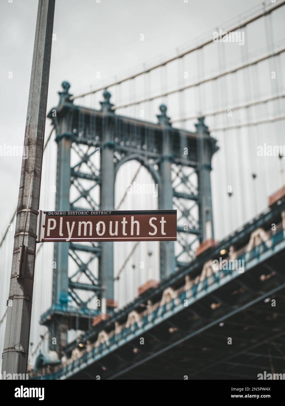 A vertical shot of the Plymouth street sign and the Brooklyn bridge in ...