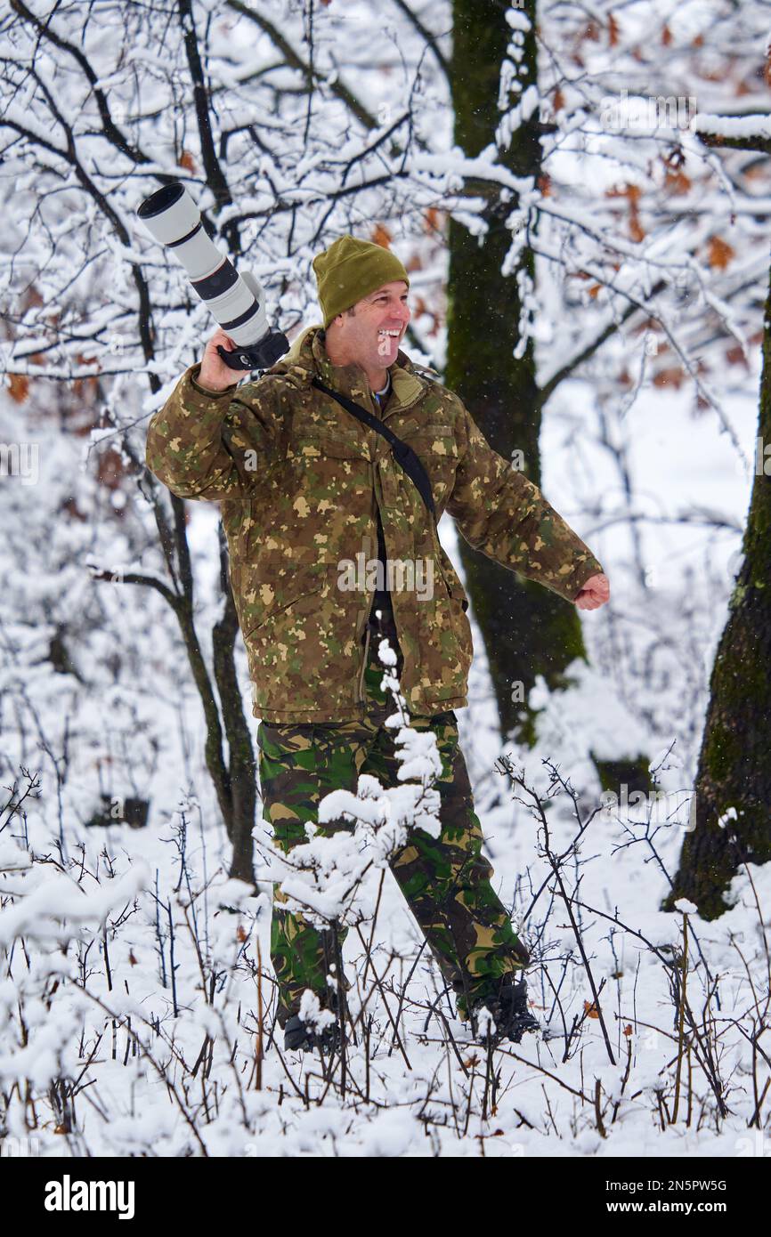 Professional wildlife photographer in a snowy oak forest with his ...