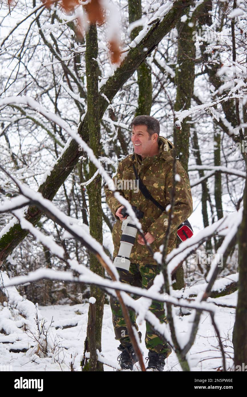 Professional wildlife photographer in a snowy oak forest with his ...