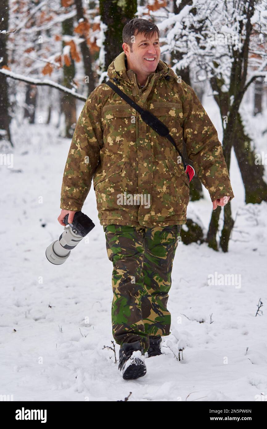 Professional wildlife photographer in a snowy oak forest with his ...