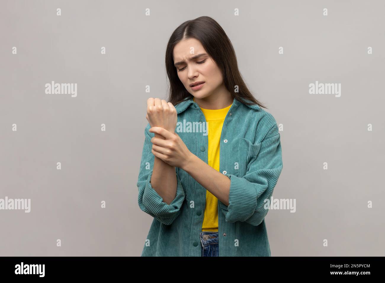 Hand or wrist pain. Portrait of sick young woman with dark hair ...